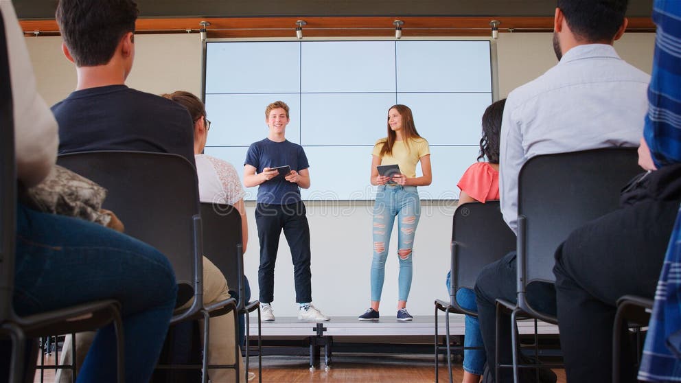 Two College Students Giving Presentation To High School or University Class in Front of Screen ...