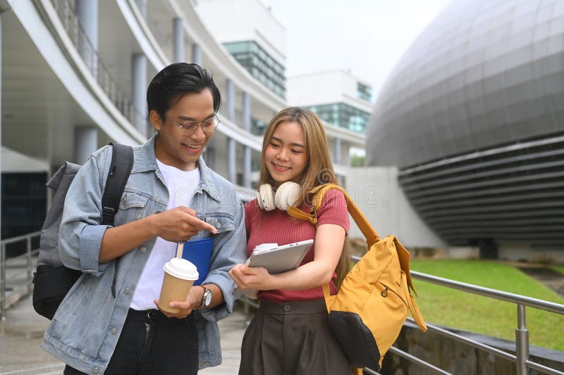Two College Students Sharing Ideas or Discussing Something while Walking on a University Campus ...
