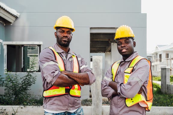 Two Confident Construction Workers Pose with Arms Crossed at a Building ...