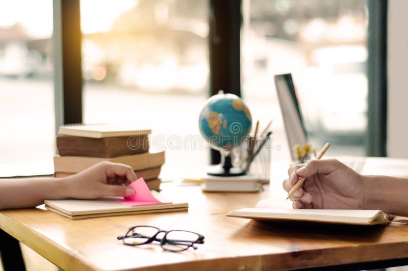 Two Confident Students Doing Homework Together while Sitting at the ...