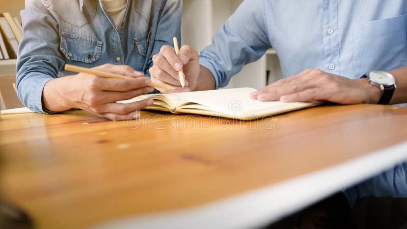 Two Confident Students Doing Homework Together while Sitting at the ...