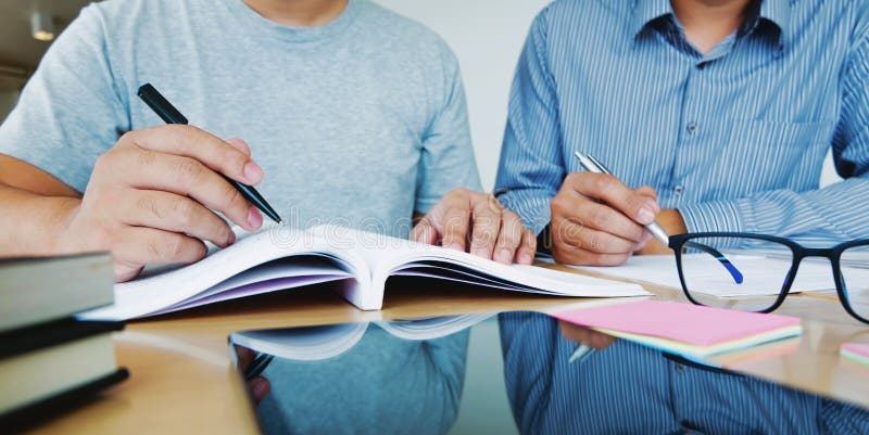 Two Confident Students Doing Homework Together while Sitting at the ...