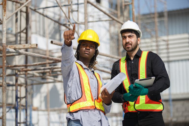 Two Construction Engineers Discussing Site Plans Outdoors. One Points ...