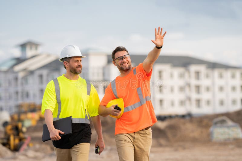 Two Construction Site Workers in Helmet Work Outdoors. Builders Workers ...