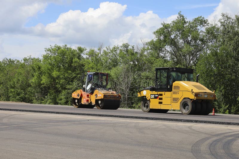 Two Construction Vehicles are on a Road, One of Which is a Caterpillar ...