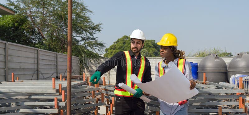 Two Construction Worker Discussing Work while Holding a Rolled-up ...