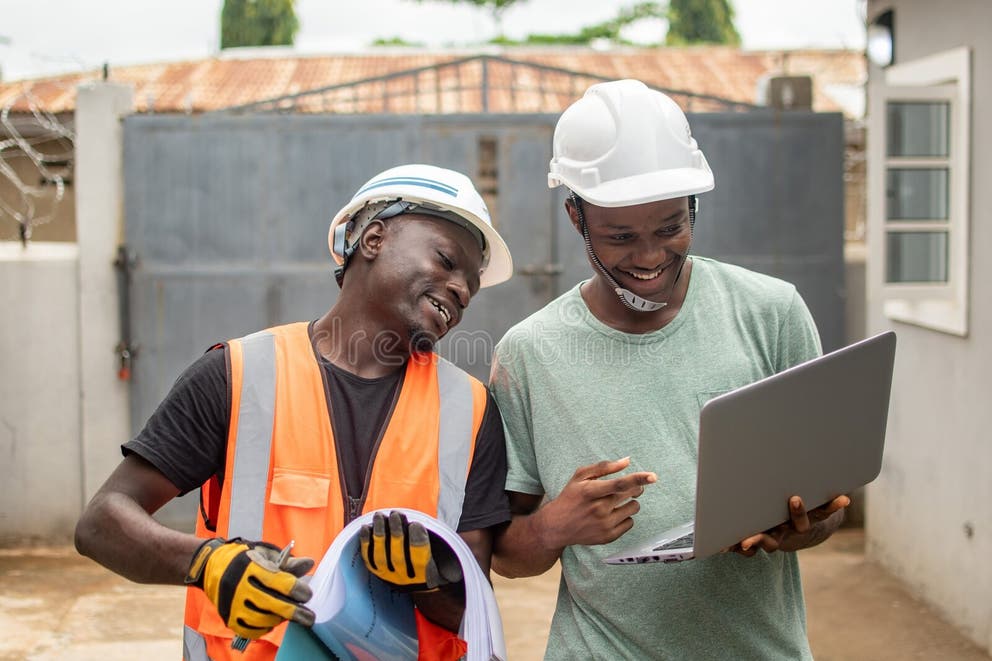 Two Construction Workers are Talking while Working on a Laptop Together ...