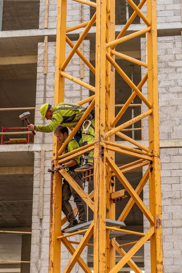 Two Construction Workers are on a Crane in a Construction Site ...