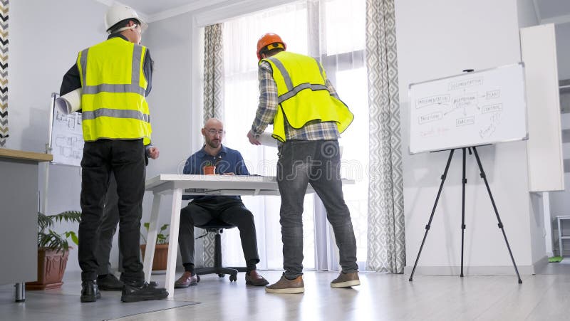 Two Construction Workers in Green Vests and Construction Helmets ...