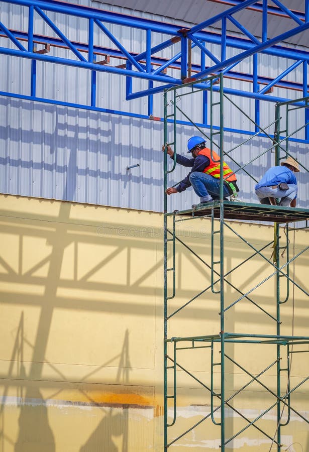 Two Construction Workers are Installing High Scaffolding for Working on ...