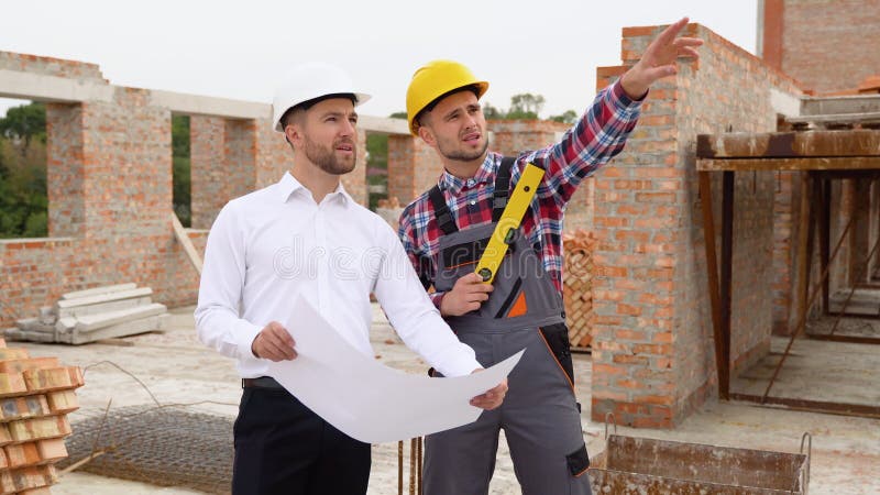 Two Construction Workers Look at an Architectural Drawing in House Construction Stock Video ...