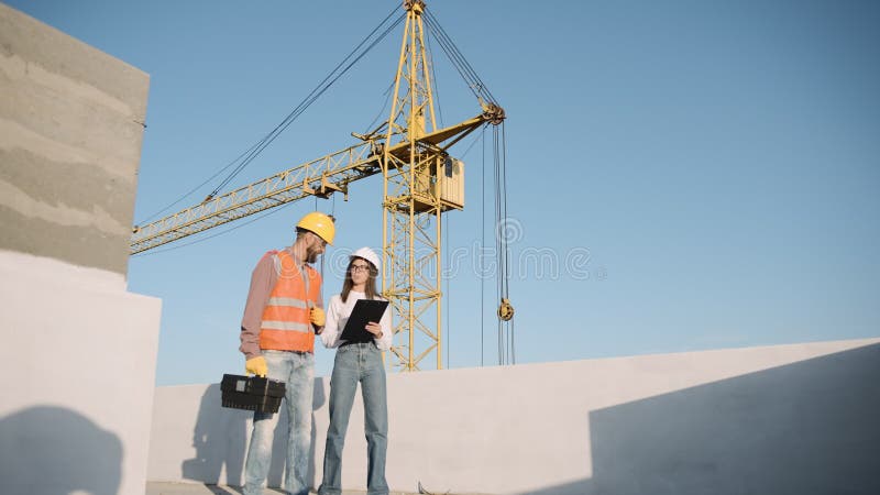 Construction Workers Discuss Project Plans at a Busy Construction Site ...