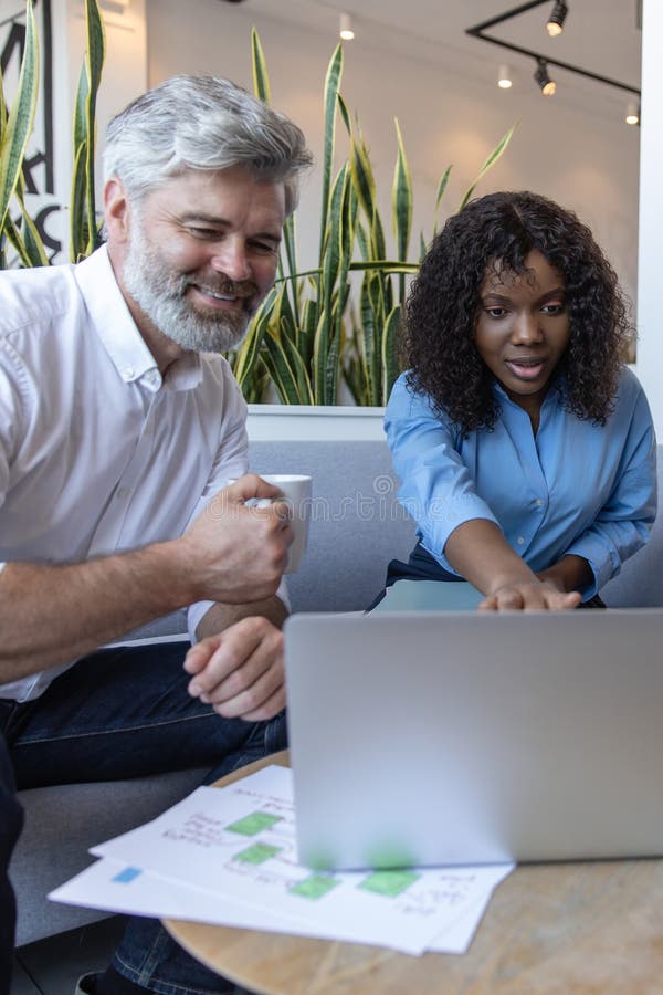 Two Creative Diverse Colleagues Sitting on Sofa in Office Collaborating ...