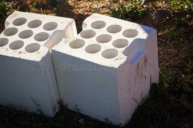 Two Cubical White Bricks with Round Holes Lying on the Ground Under ...
