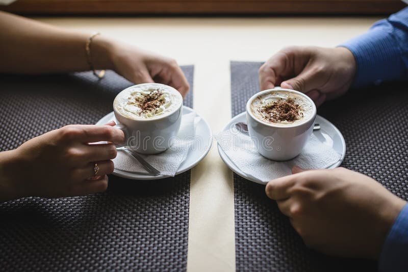 Two Cups of Coffee in Hands of Man and Woman at Table in Cafe Closeup ...