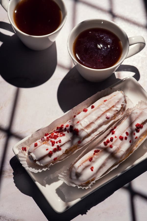 Two Cups of Tea and Two Eclairs with White Icing and Red Sprinkles on a ...