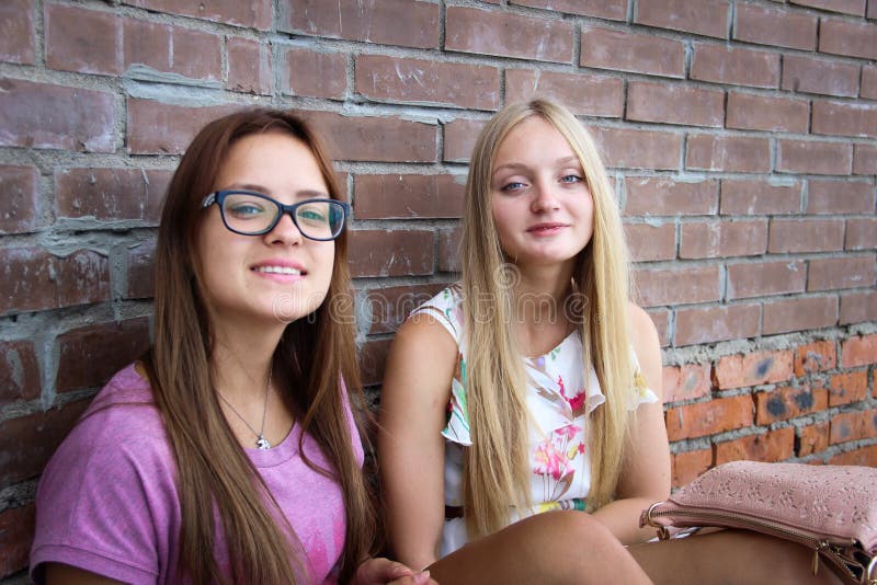 Two Cute Girls Sitting in Front of a Brick Wall Stock Photo - Image of ...