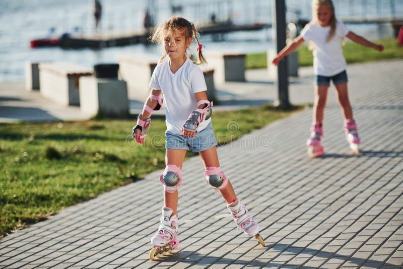 Two Cute Kids Riding by Roller Skates in the Park at Daytime Stock ...