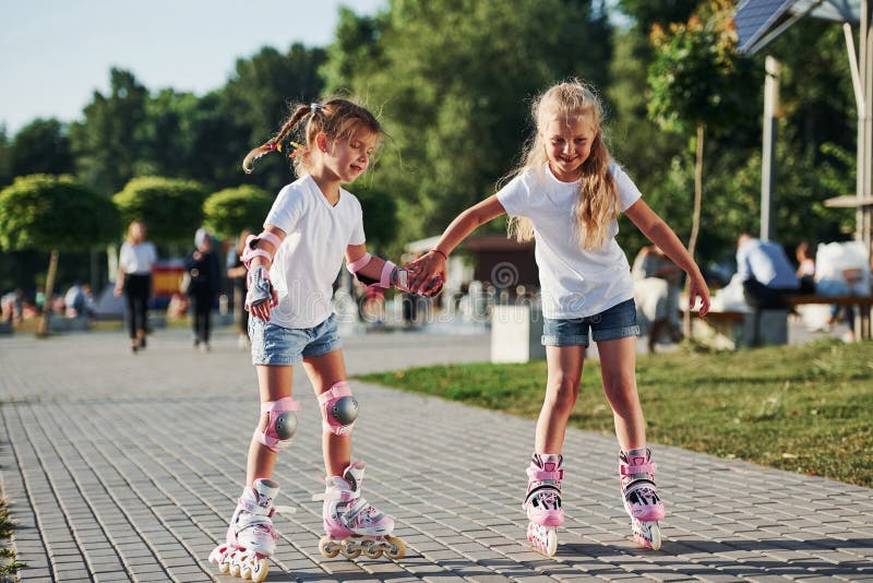 Two Cute Kids Riding by Roller Skates in the Park at Daytime Stock ...