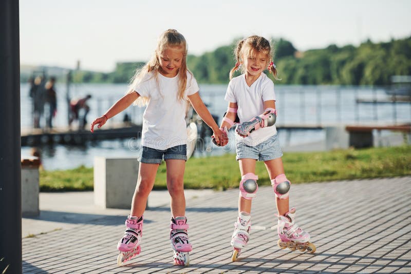 Two Cute Kids Riding by Roller Skates in the Park at Daytime Stock ...