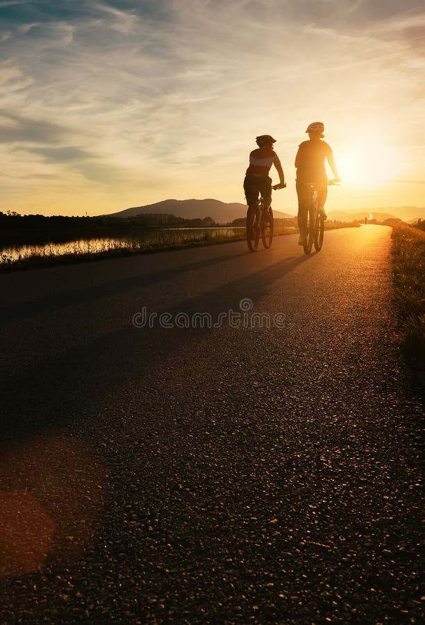 Two Cyclists are on Sunset Road Stock Image - Image of cycle, bicycling ...
