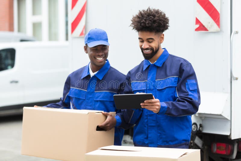 Two Delivery Men Looking at the Digital Tablet Stock Image - Image of ...