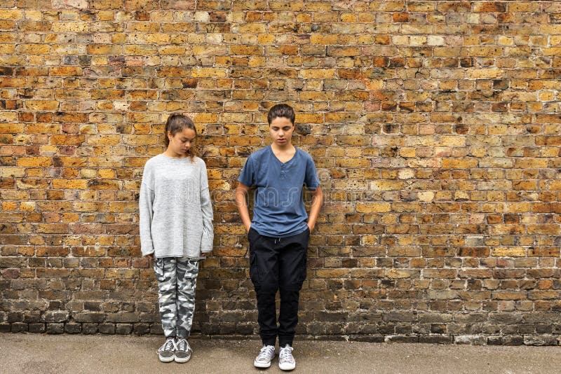 Two Depressed Young Teens Stand in Front of a Brick Wall Stock Image ...