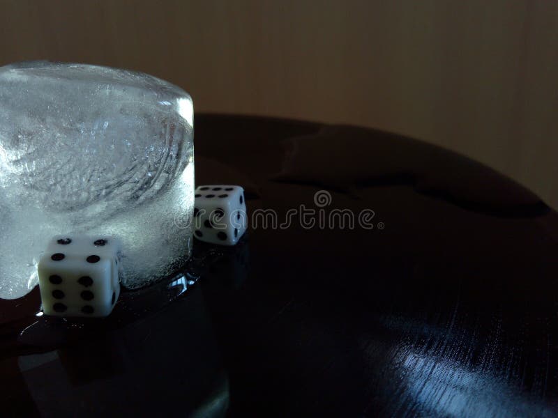 Two Dice and a Cold Block of Ice with Bubbles are Placed on a Black ...