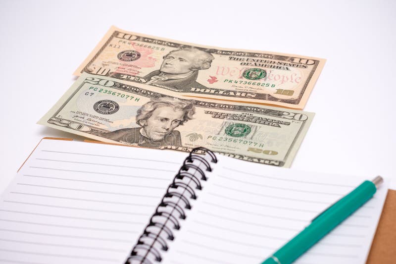 Two Different Colored Bills are on a Table Next To a Pen and a Notebook ...