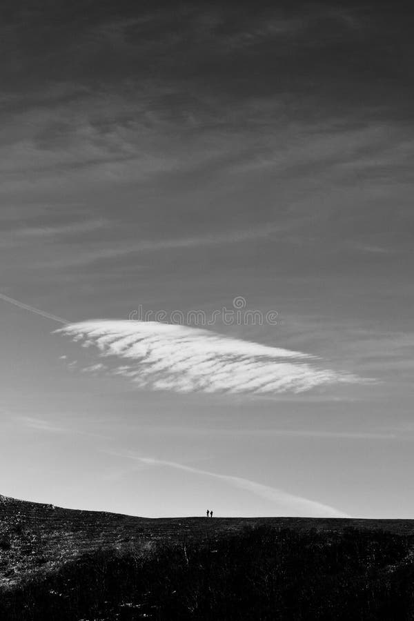 Two Distant People on a Mountain Peak with a Cloud Above Them Stock ...
