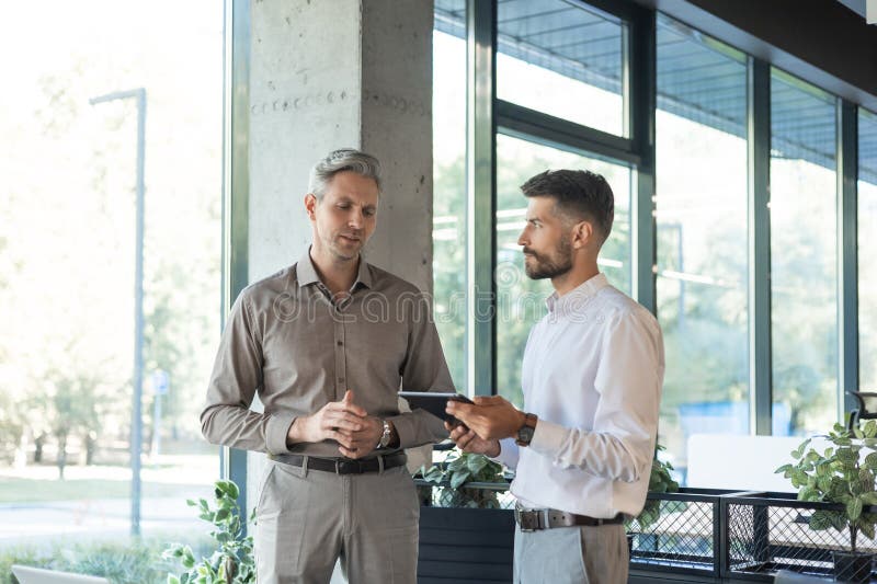 Two Diverse Business Partners Standing and Discussing Project Working ...