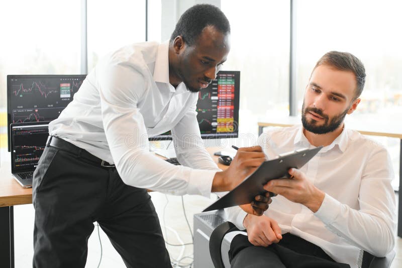 Two Diverse Colleagues Traders Talking To Each Other, Sitting in the ...