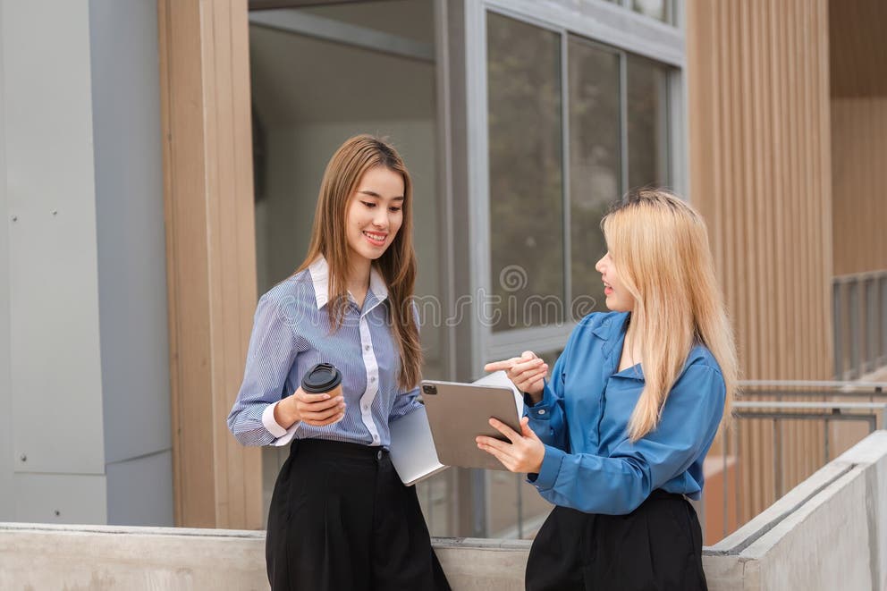 Diverse Women Discussing Work while Holding a Coffee and Using a Tablet ...