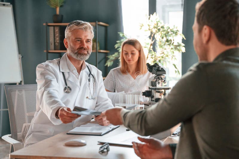 Two Doctors Consult a Patient in a Clinic Stock Photo - Image of adults ...