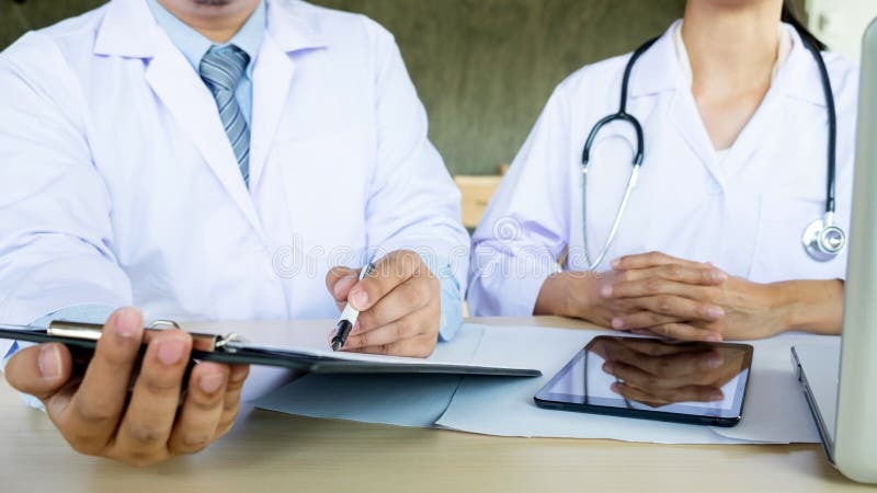 Two Doctors Discussing Patient Notes in an Office Pointing To a Stock ...