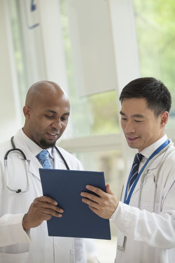 Two Doctors Looking Down and Consulting Over Medical Record in the ...