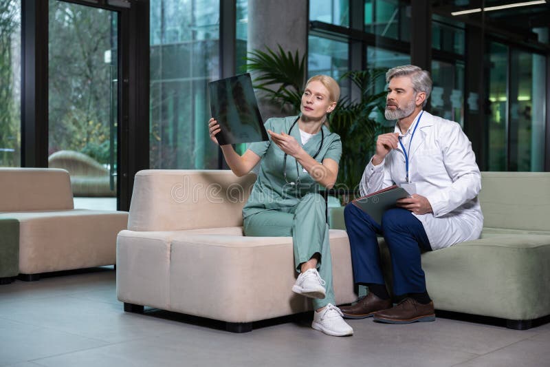 Two Doctors Sitting Next To Each Other and Discussing Xray Results ...