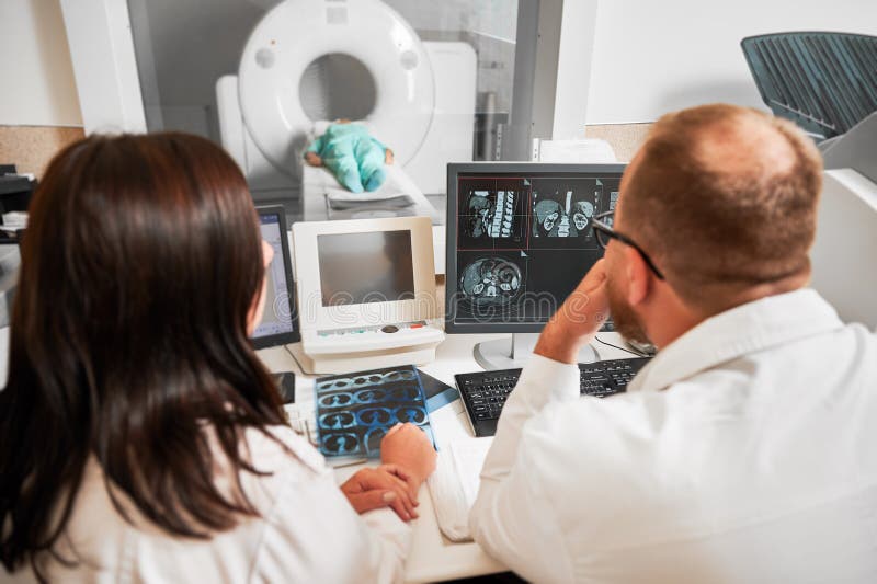 Two Doctors Sitting, Working at Computer, Making MRI. Stock Image ...