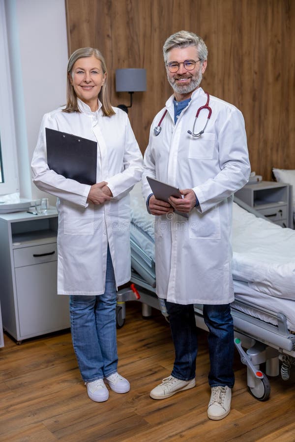 Two Doctors Standing in a Room in Clinic and Looking Positive Stock ...