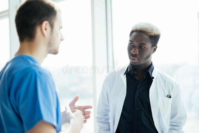Mixed Race Two Doctors Talking As they Walk through Modern Hospital ...