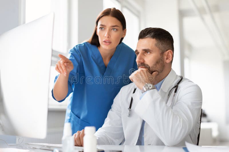 Two Doctors Talking and Using Computer, Discussing Diagnose and Tests ...