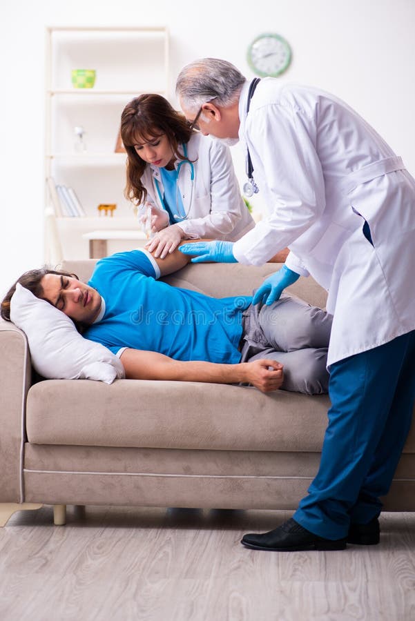 Two Doctors Visiting Sick Young Man at Home Stock Photo - Image of ...