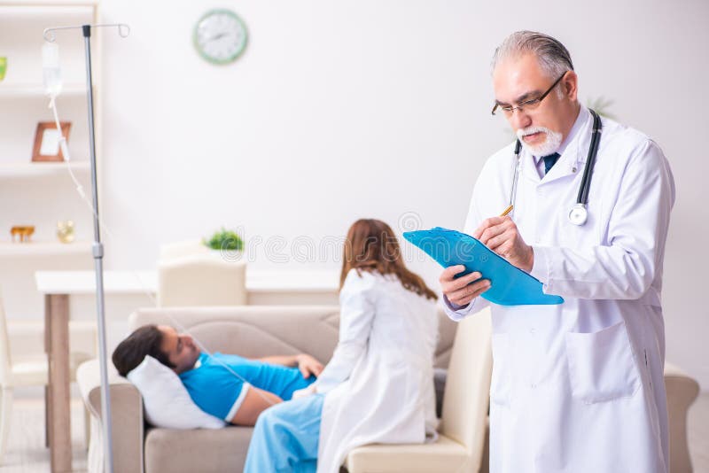 Two Doctors Visiting Sick Young Man at Home Stock Photo - Image of ...
