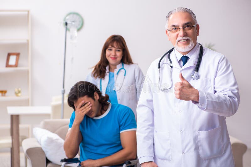 Two Doctors Visiting Sick Young Man at Home Stock Image - Image of ...