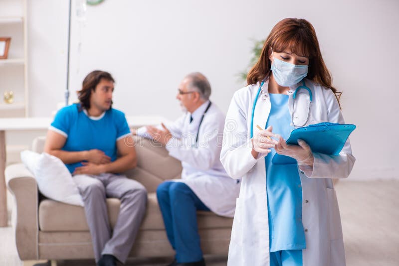 Two Doctors Visiting Sick Young Man at Home Stock Photo - Image of ...