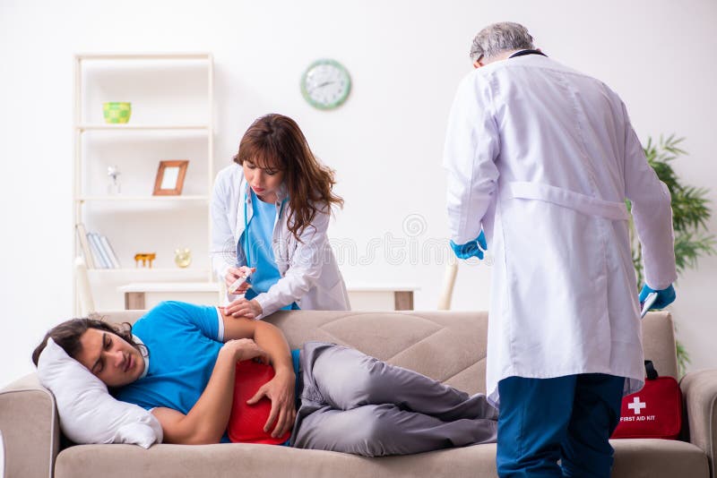 Two Doctors Visiting Sick Young Man at Home Stock Photo - Image of ...