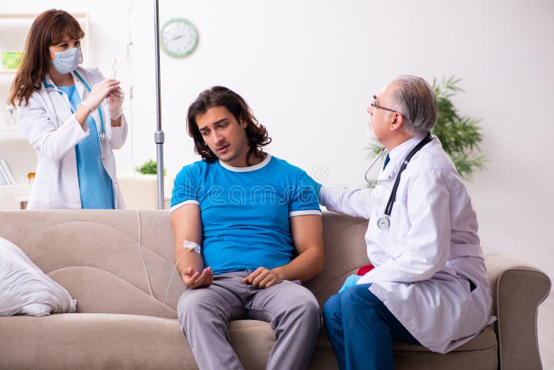 Two Doctors Visiting Sick Young Man at Home Stock Image - Image of care ...