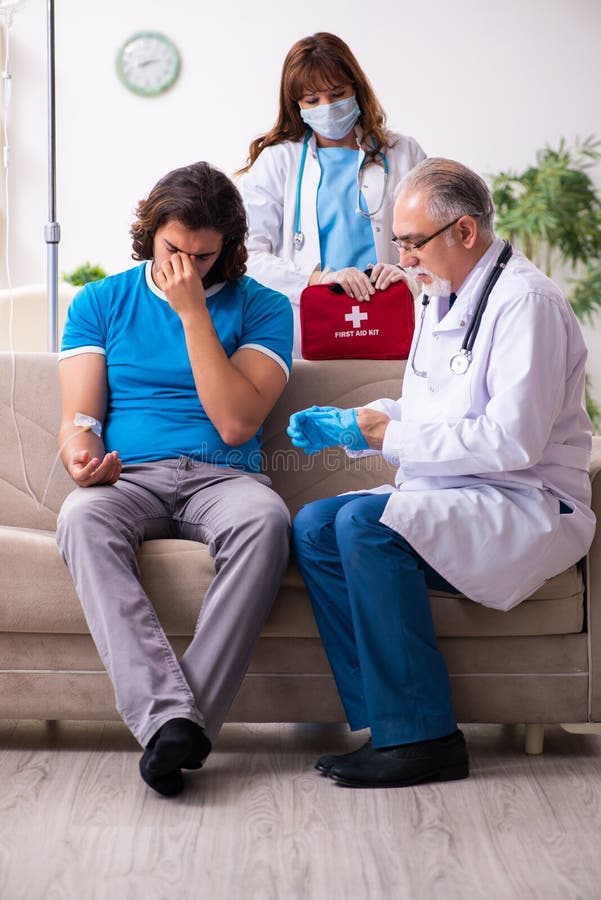 Two Doctors Visiting Sick Young Man at Home Stock Image - Image of ...