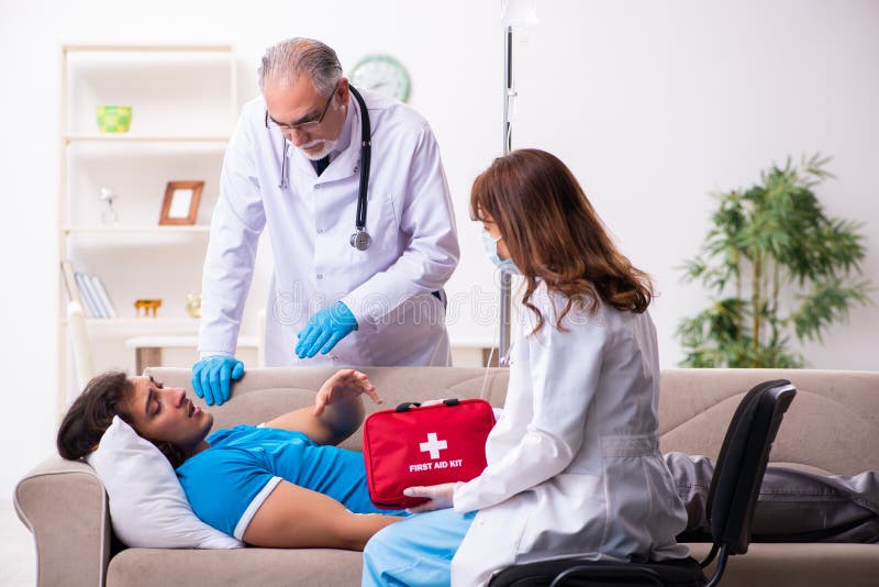 Two Doctors Visiting Sick Young Man at Home Stock Photo - Image of ...