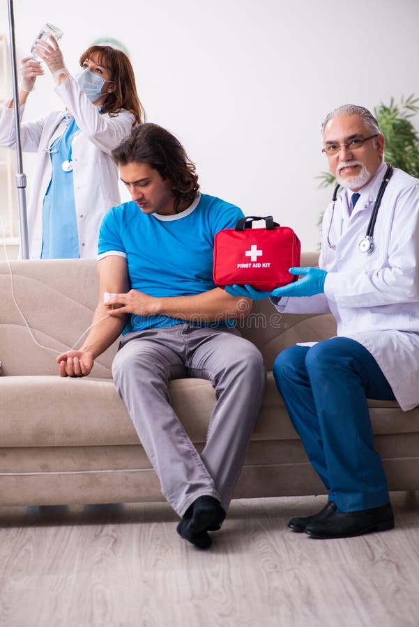 Two Doctors Visiting Sick Young Man at Home Stock Image - Image of ...